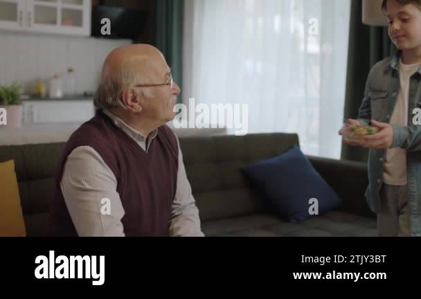 Boy offering candy in bowl to his old grandfather.Little boy offering ...