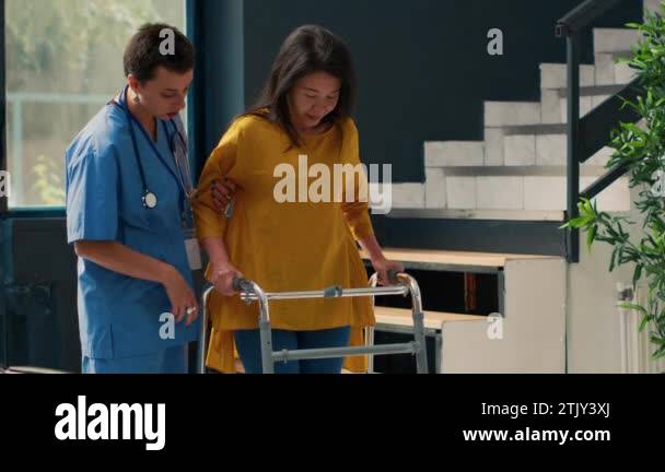 Health specialist supporting asian patient to walk with leg fracture ...