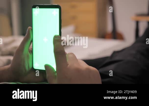 Man lying on couch using smartphone with chroma key green screen at ...