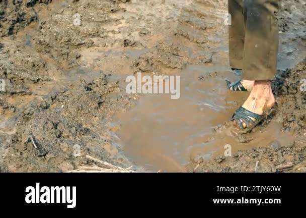 Mens feet in a puddle and swamp. A man stomps in a puddle in slippers ...