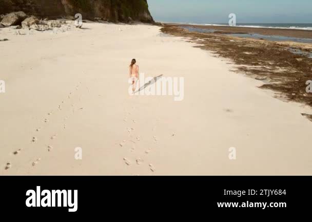 Naked woman walking and sunbathing at sandy beach near ocean. Aerial ...