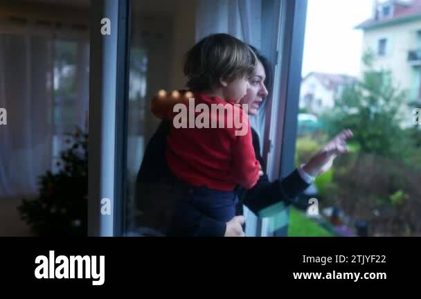 Mother holding toddler in arms and locking apartment window. Woman ...