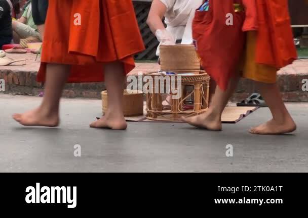 Feet of monks at the traditional sacred alms-giving ceremony. Local ...