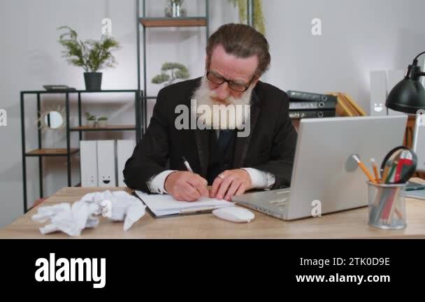Angry furious senior man working at office throwing crumpled paper ...
