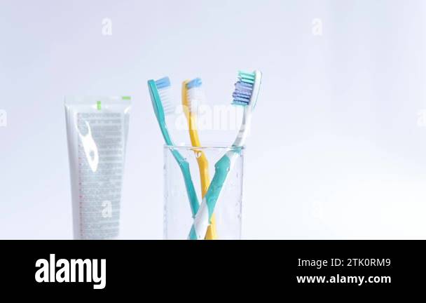 A woman's hand takes a toothbrush. Toothbrushes in a glass beaker on a ...