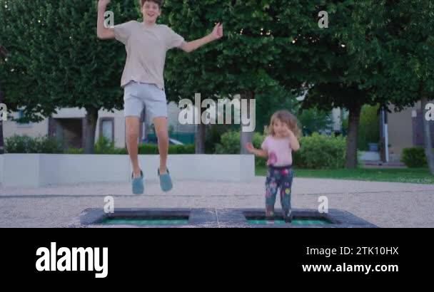 Happy children jumps very high on a trampoline in park. Brother with ...