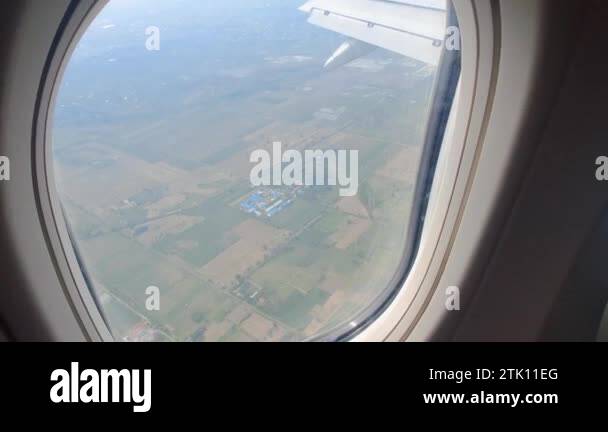 Commercial airplane windows show the expanse of rice fields to the city ...