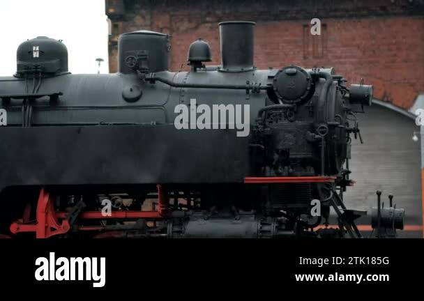 Black steam locomotive with steam propulsion system, in the rain at the ...