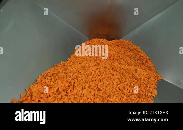 Pouring cone-shaped chips onto the production line in a food factory ...