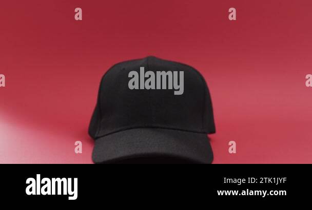 Video of black baseball cap and copy space on red background. Headgear ...