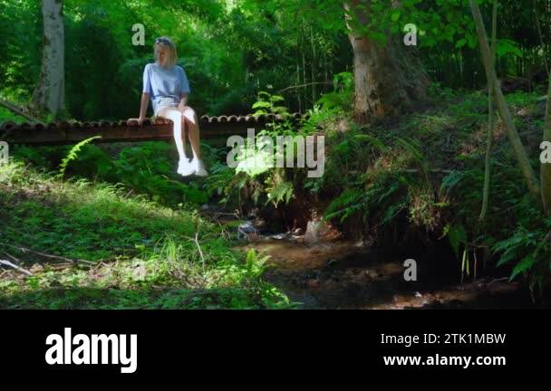 Sad depressed girl on bridge in forest by river. Young beautiful ...