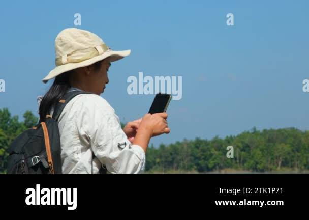 Female ecologist with backpack using mobile phone taking picture of ...