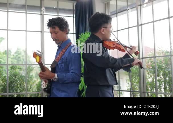 Two Asian musicians play classical instruments violin and electric ...