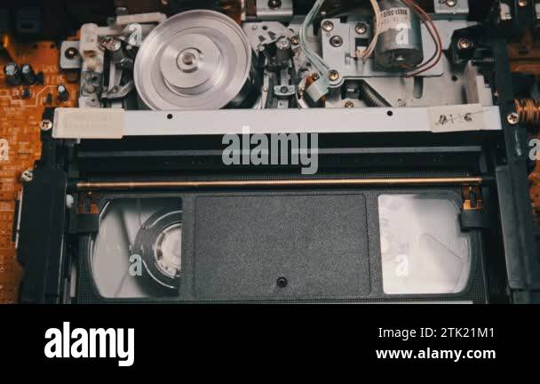 VHS video tape putting inside a VCR recorder and plays. Vintage VHS mechanism of videotape ...