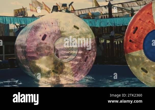 Inflatable Water Rollers. Water attractions. Children playing inside an ...