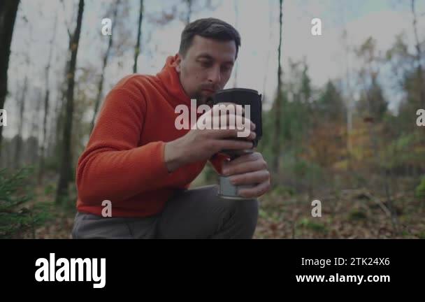 Man hiker sets up system for cooking while camping in woods. Traveler ...