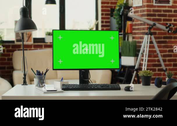Greenscreen display on monitor with empty table in living room, workspace with chroma key blank ...