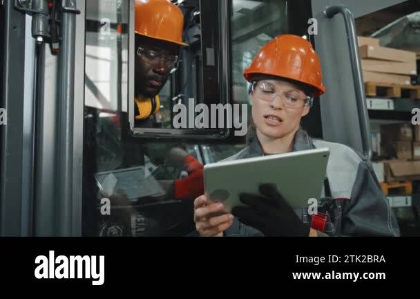 Female engineer with tablet computer talking to African American male ...