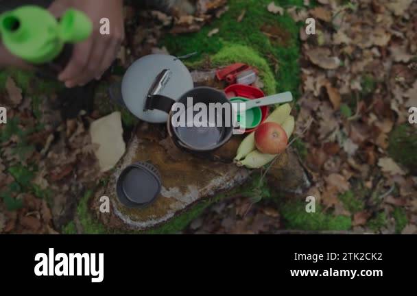 Traveller throws water into an integrated cooking system on a stump in ...