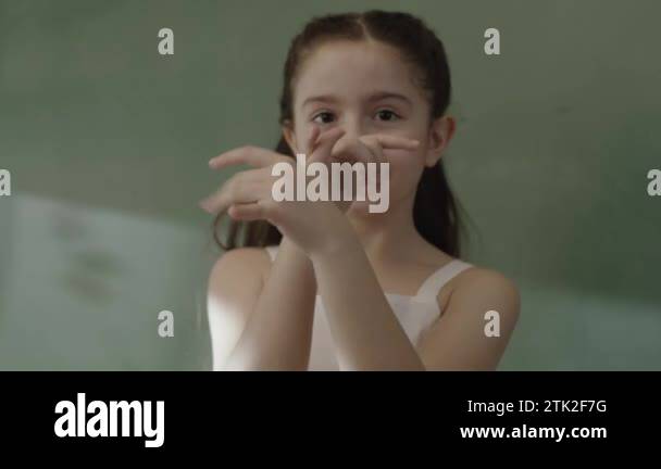 Little girl having fun, making fun by putting her hands on her nose ...