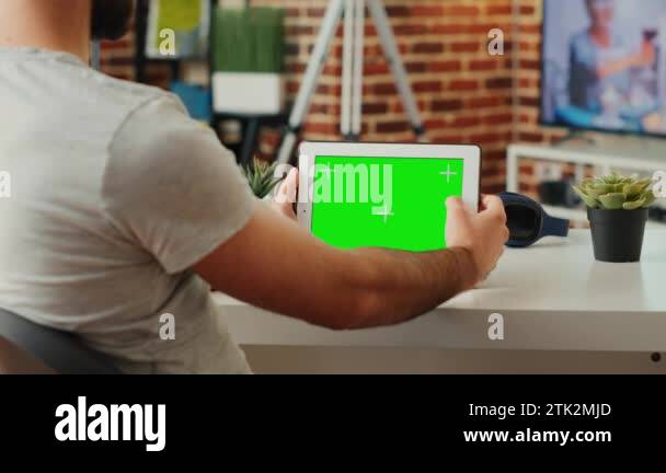 Young man holding modern device with horizontal greenscreen template in ...