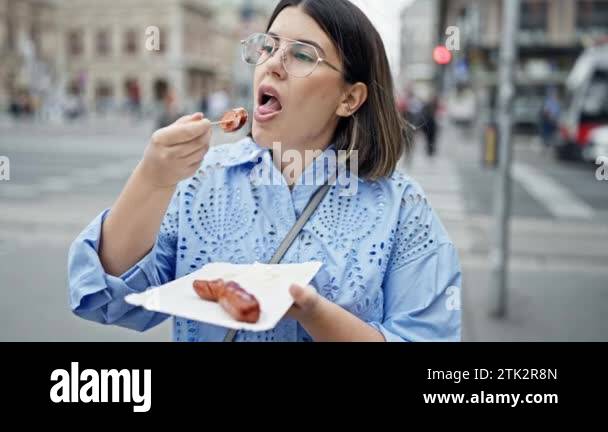 Young beautiful hispanic woman eating K??sekrainer sausage in the streets of Vienna Stock Video ...