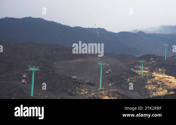 View of cable cars moving over volcanic landscape emitting smoke. High ...
