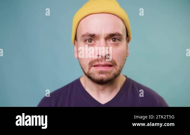 Close up young mad angry displeased guy in yellow cap looking at camera ...
