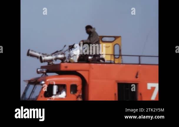 Firefighters sitting at fire cannons on top of trucks at a military ...