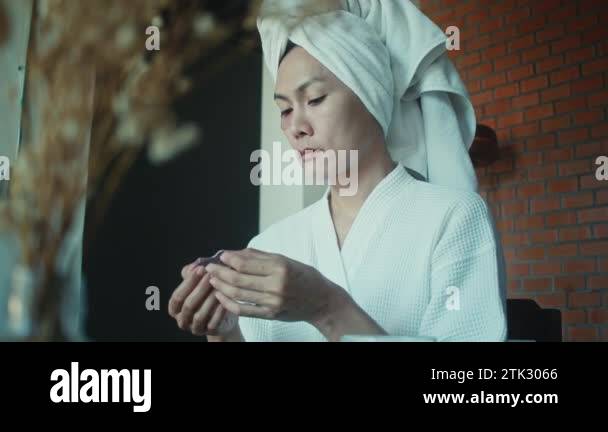 Young asian transgender queer man does his makeup in his room while ...