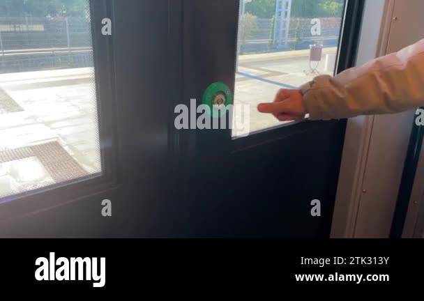 The hand presses the stop button on the train. Train car door with ...