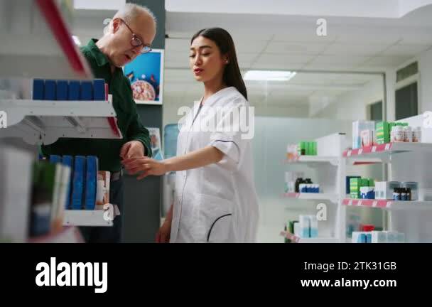 Asian pharmacist explaining cardiology drugs to senior man, talking ...