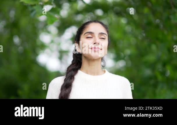 Young indian woman enjoying nature taking deep breaths of fresh air ...