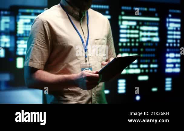 Experienced engineer inspecting operational server racks in computer network security data ...