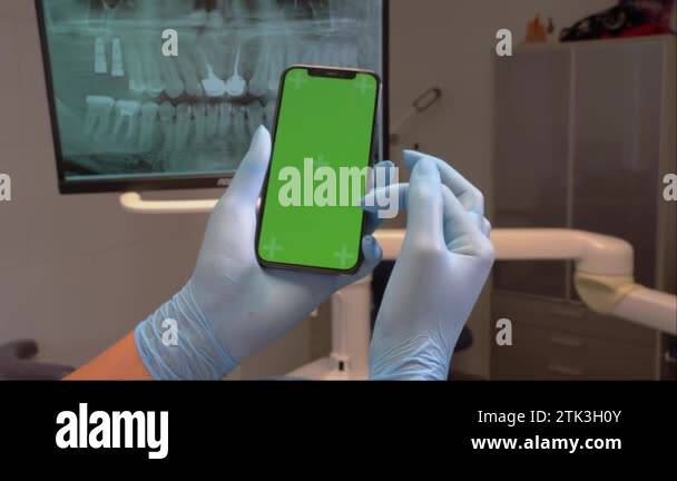 Closeup dentist hands sterile glove hold green screen cellphone at ...