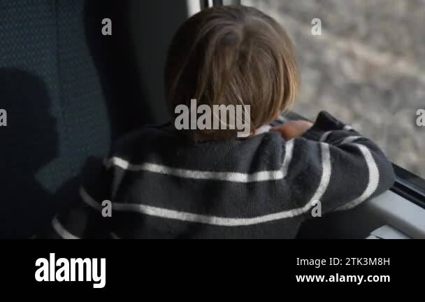 One happy child traveling on high speed train staring out window. Back ...
