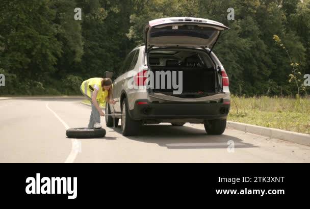 Girl changing a punctured tire at the car. Repair of cars on the road ...