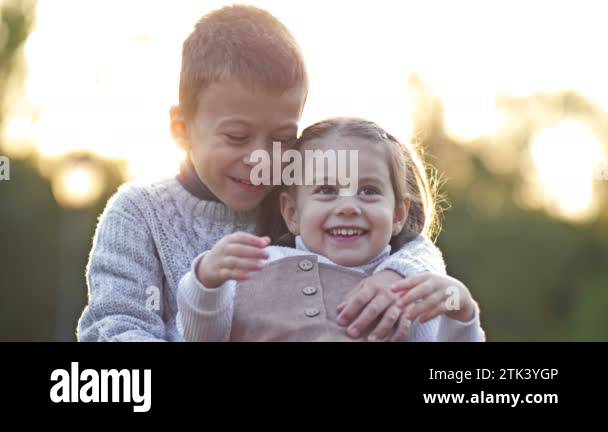 Boy gives his little sister a gentle hug and a girl playfully touches ...