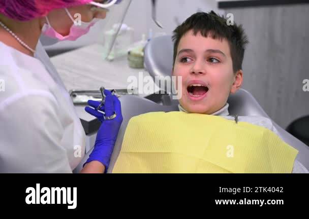 Teenage child boy patient getting a dental anesthesia, sitting on chair ...