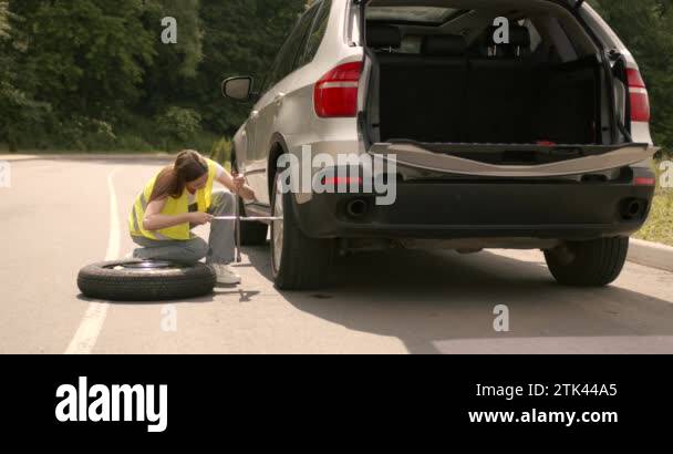 Girl changing a punctured tire at the car. Repair of cars on the road ...