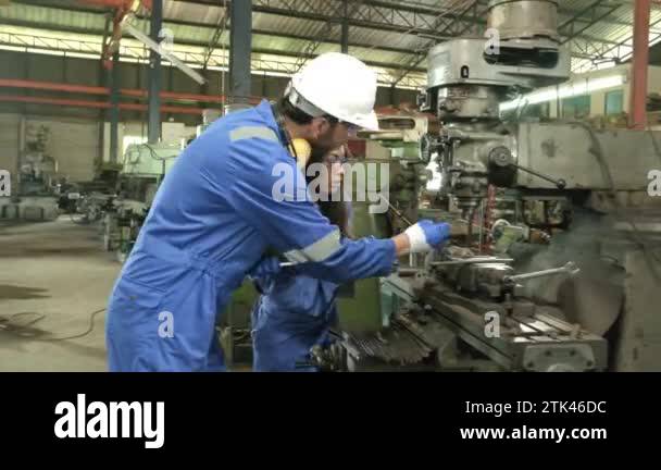 Two industrial workers in protective and safety uniforms and hardhats ...