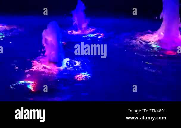 Fountain in water illuminated by colorful lights at night. Flow of ...