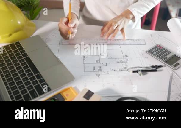 Architectural project workplace. Architect typing laptop keyboard to review design of house ...