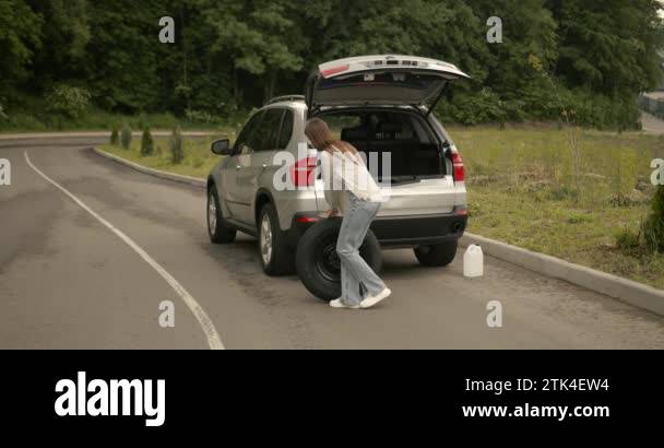 Girl changing a punctured tire at the car. Repair of cars on the road ...