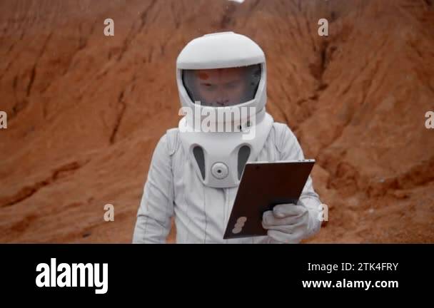 An astronaut in a special suit and helmet walks with a tablet on the ...
