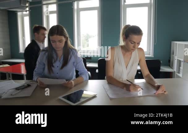 Office staff work in a row at same table, looking at documents, and in tablet screen Stock Video ...