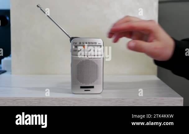 A man's hand Tunes a radio wave on the radio on an old wooden table ...