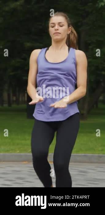 Vertical Screen: Fit woman doing exercises for legs, running in place ...