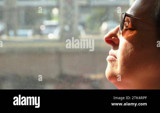 A 52-year-old woman finds solace on a commuter rail. With eyes gently ...