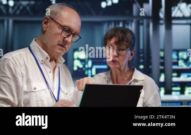 Efficient technical support executives looking around server hub, using ...